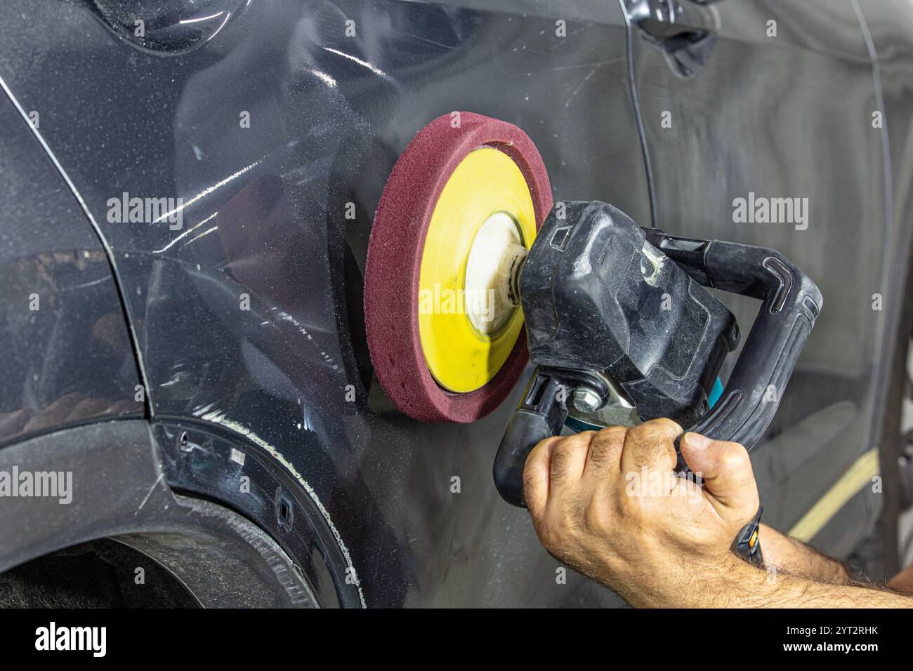 Professional car detailer holds air random orbital sander or dual ...