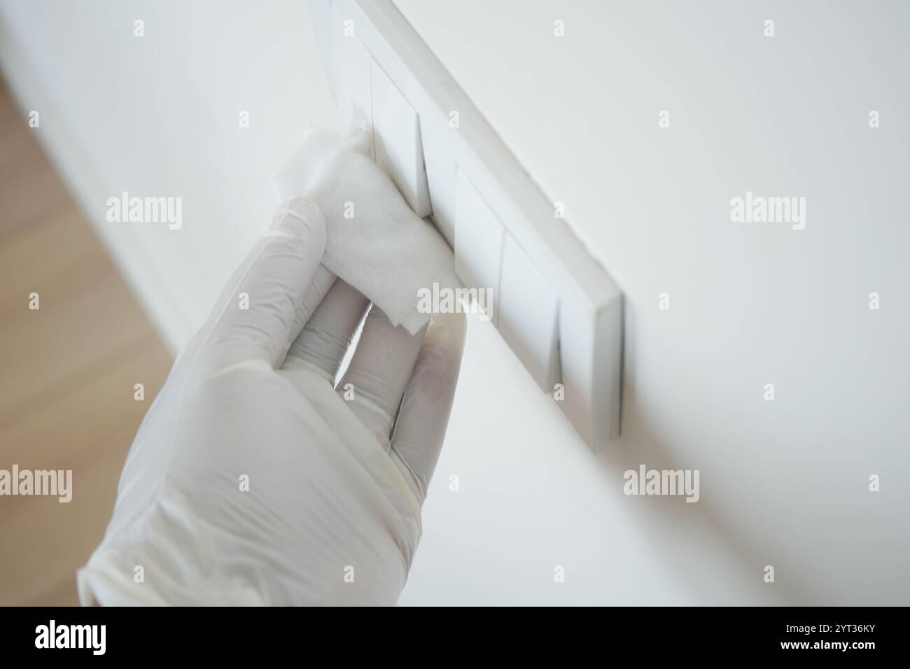 Using a gloved hand to carefully clean the wall switch thoroughly and ...