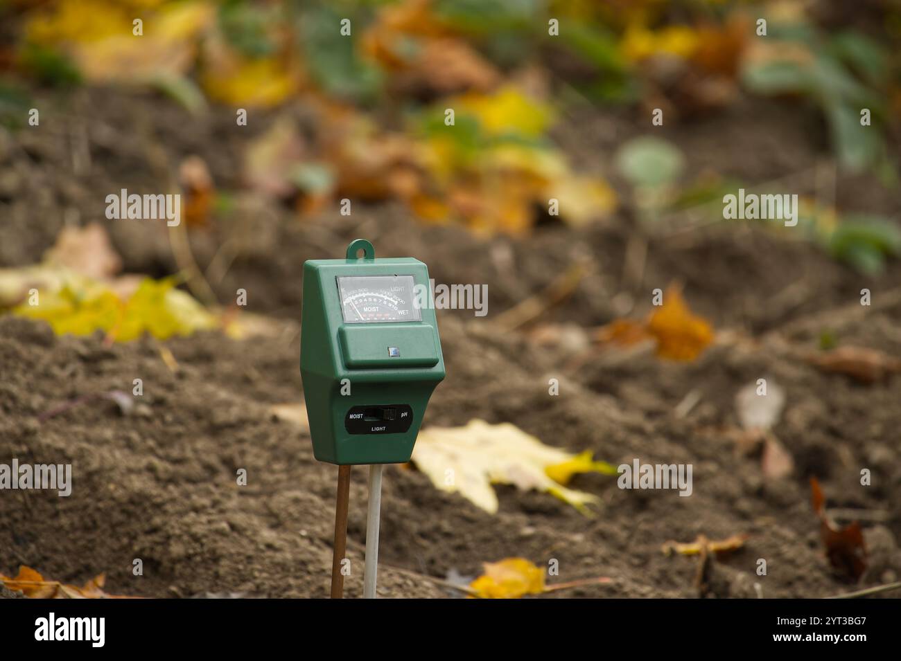 Green soil moisture meter placed in a garden setting. The close-up ...