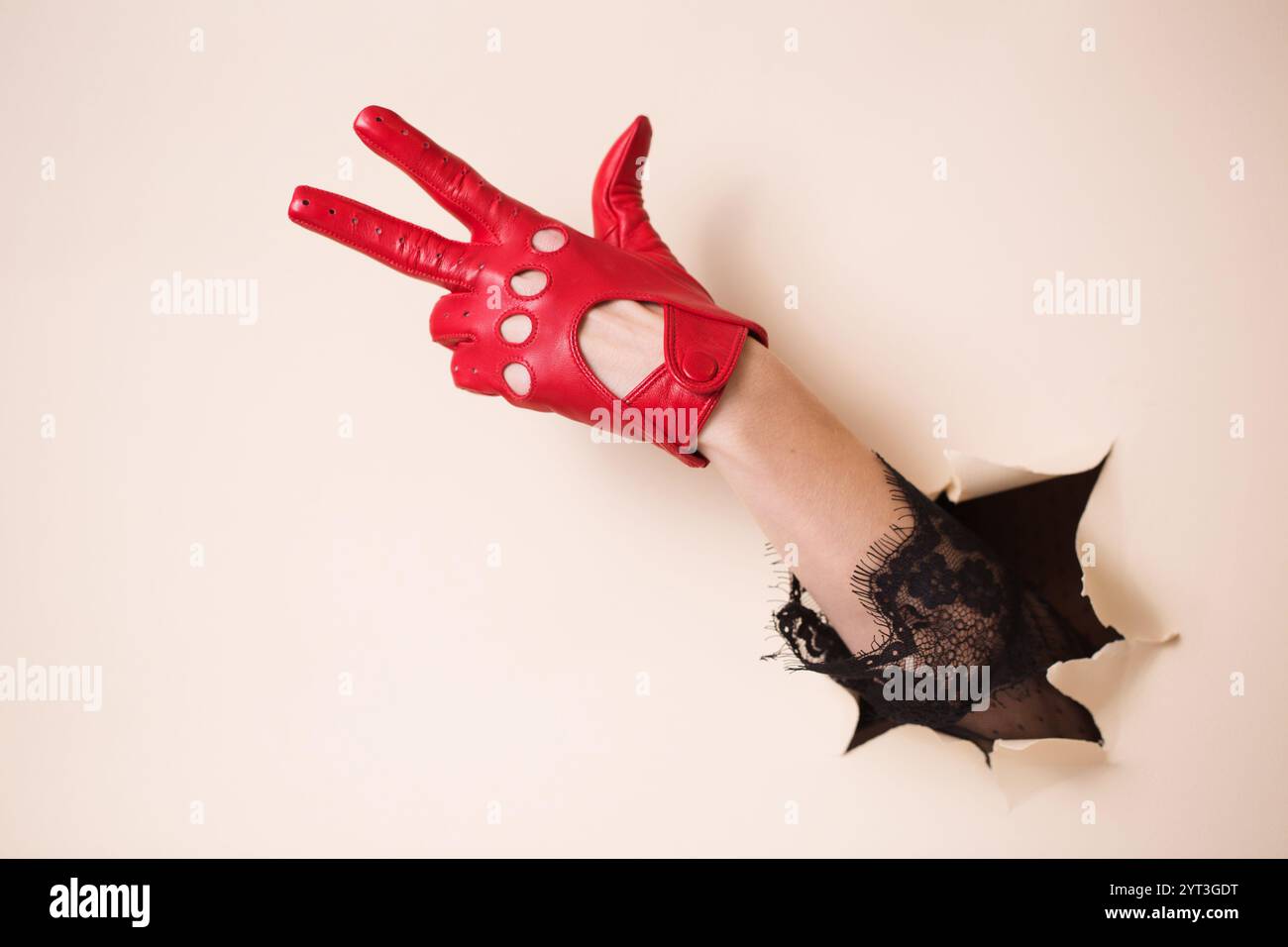 A woman's hand in a red leather car glove shows two fingers gesture ...