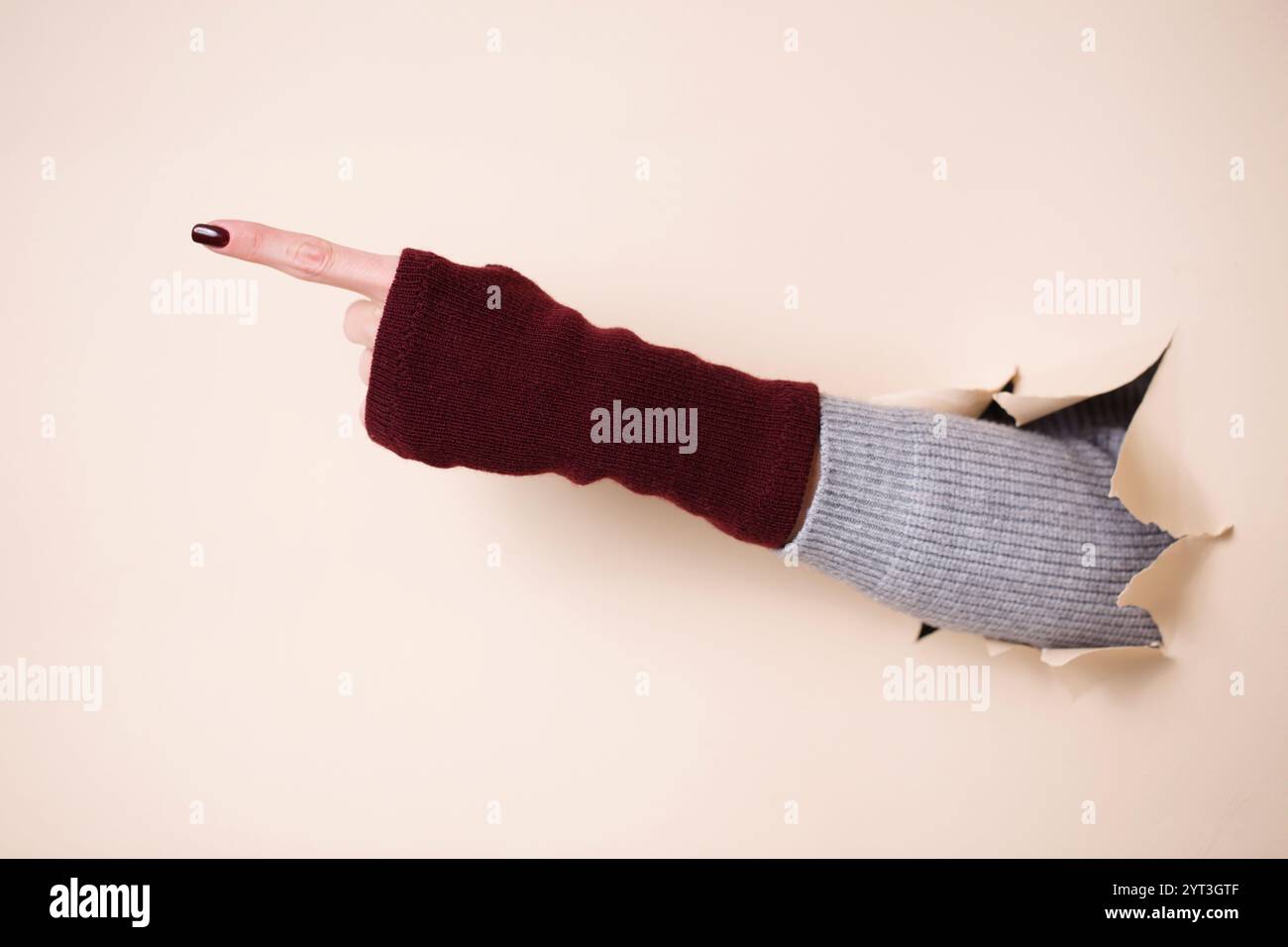 A woman's hand in a knitted burgundy mitten shows a gesture. The hand ...