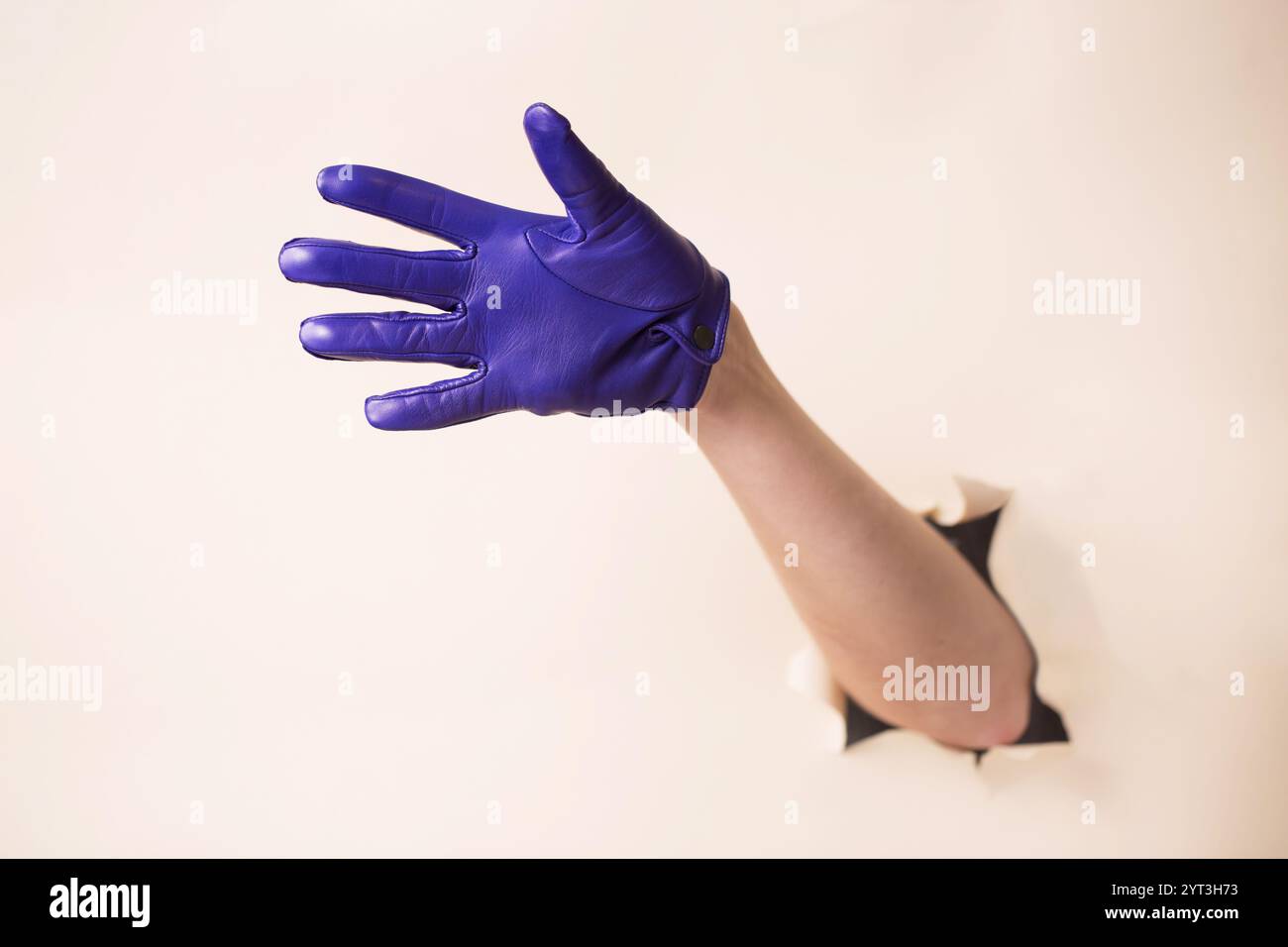 A woman's hand in a leather glove shows a gesture. The hand is pushed ...