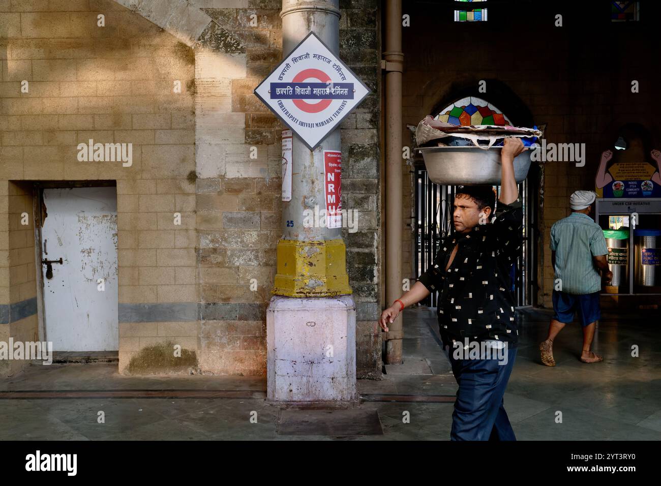 A porter carrying goods on his head walking on a platform at ...