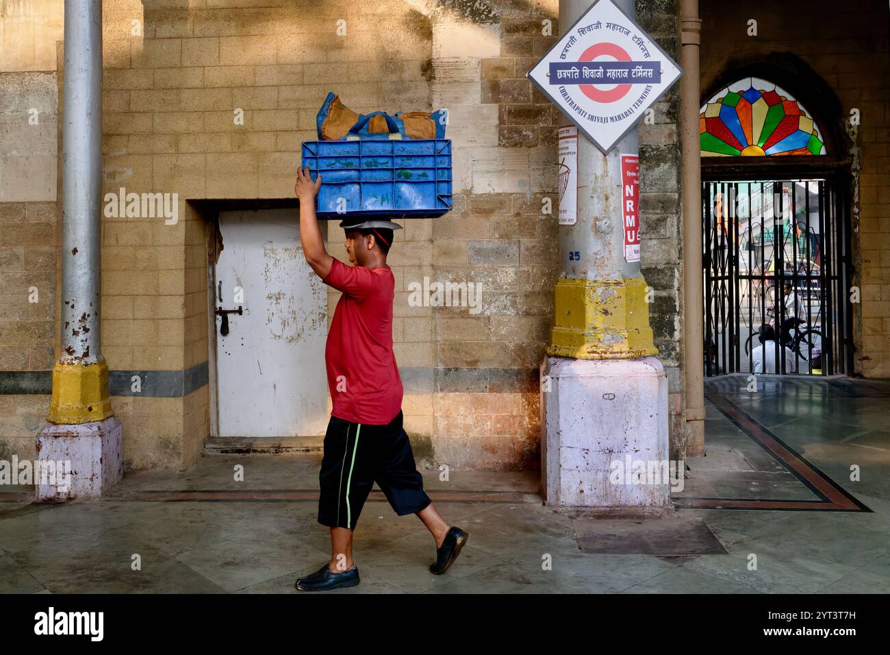 A porter carrying goods on his head walking on a platform at ...