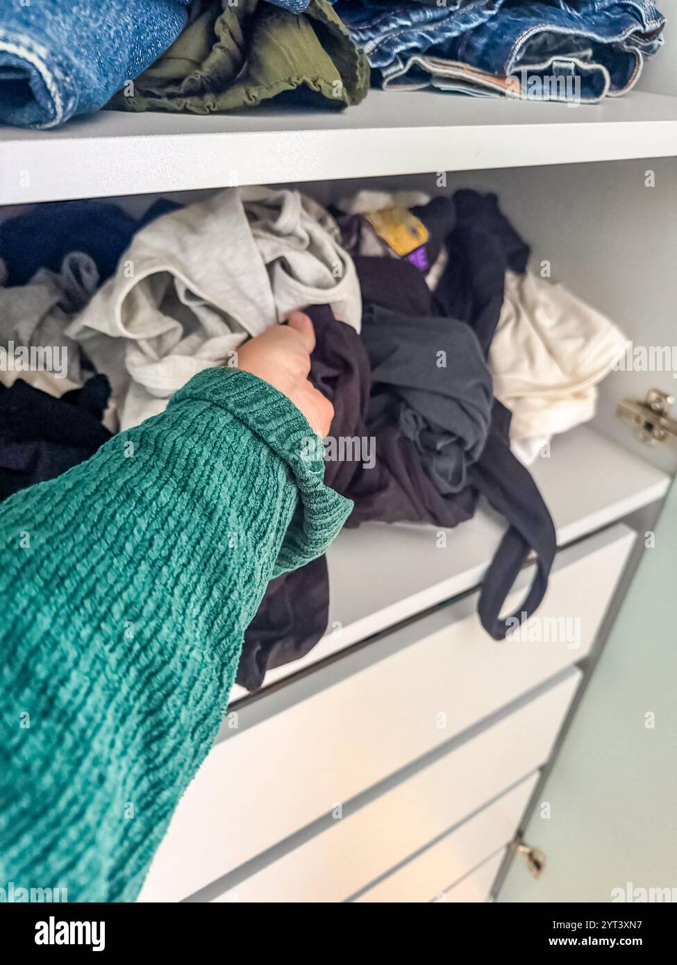 female hands trying to Organise closet with unfolded clothes in dressing room . High quality ...