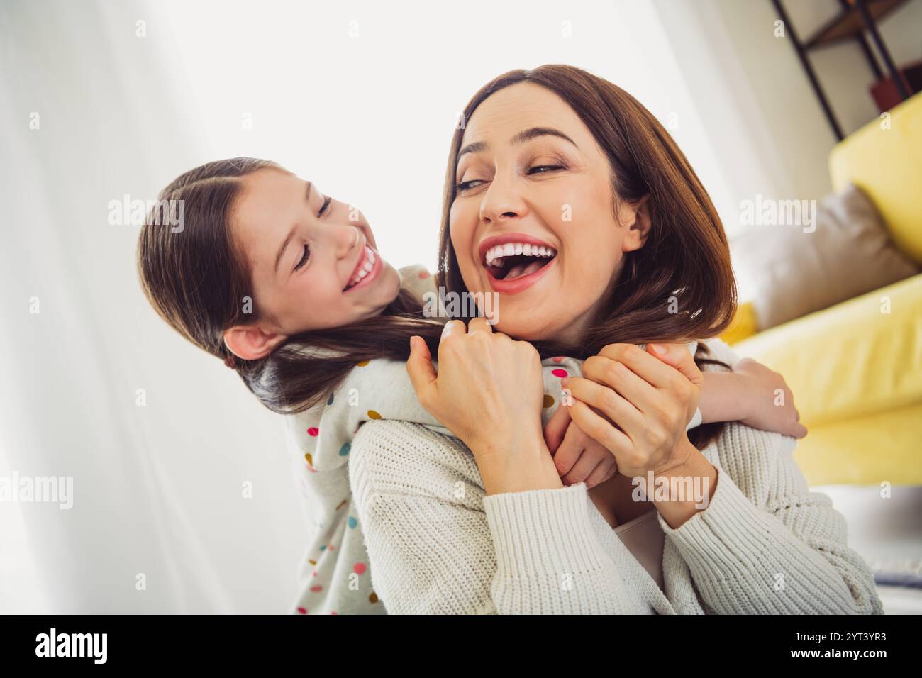 Joyful moment shared between a young mother and her daughter indoors during a relaxing spring ...