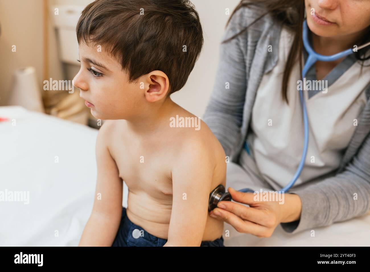 Doctor using stethoscope examining lungs of child during medical ...
