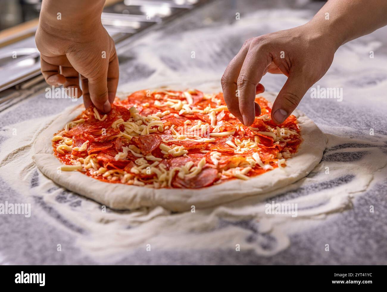 Hands preparing a pizza or making a homemade pepperoni pizza. Cook hand ...