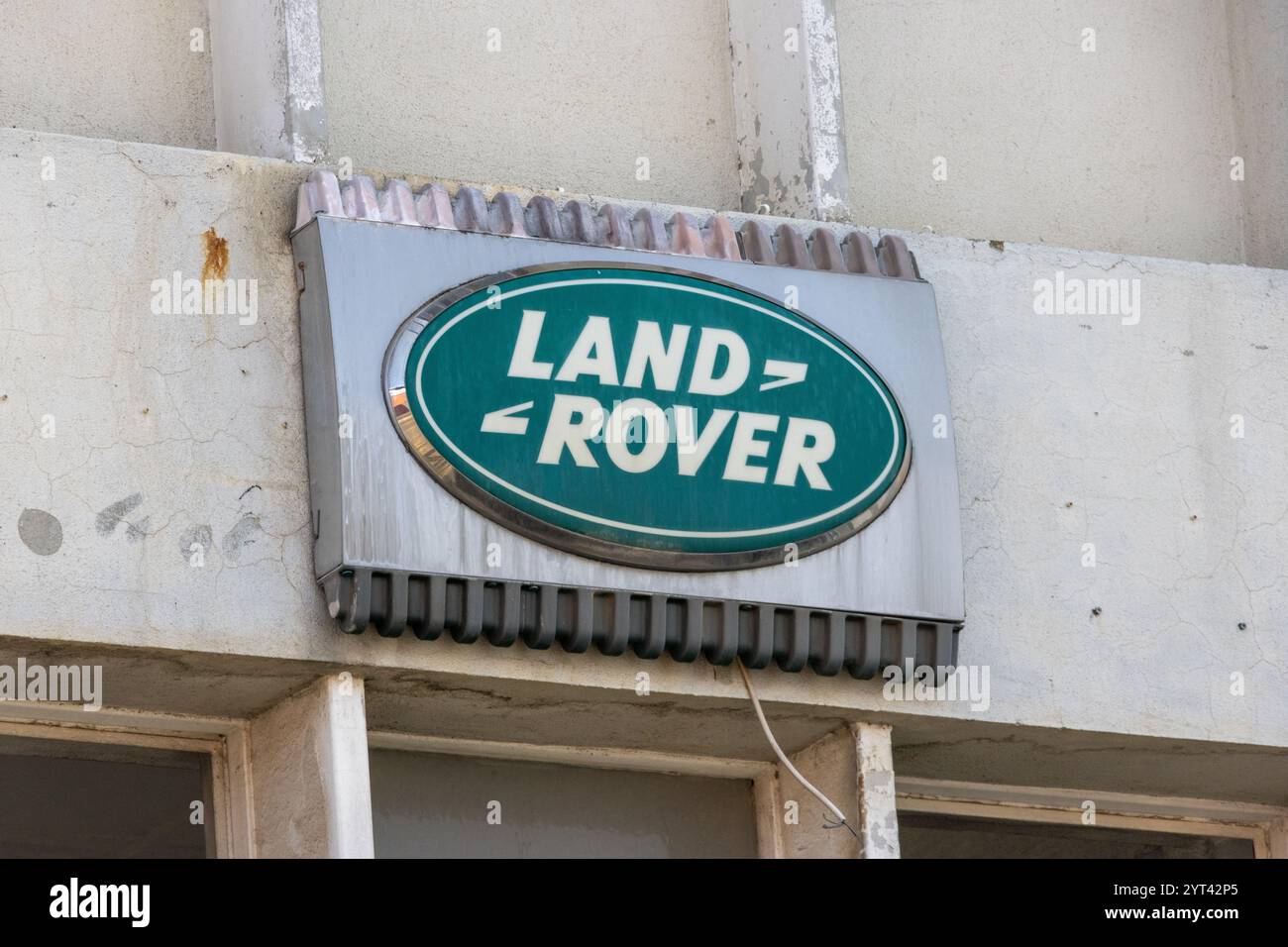 Green and white land rover logo fixed on a weathered building facade ...