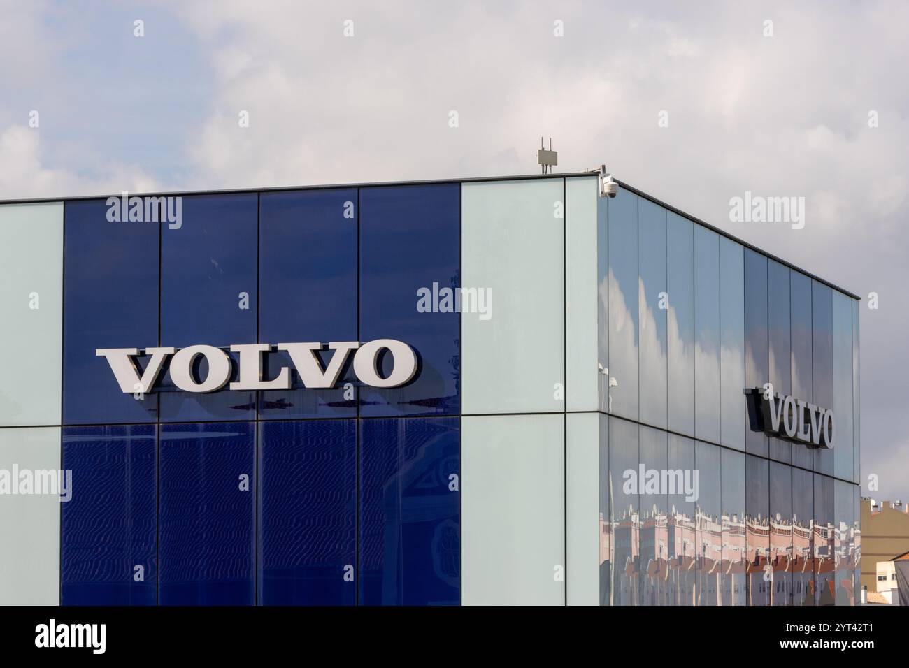 Volvo logo displayed on a modern glass building, reflecting the cloudy ...