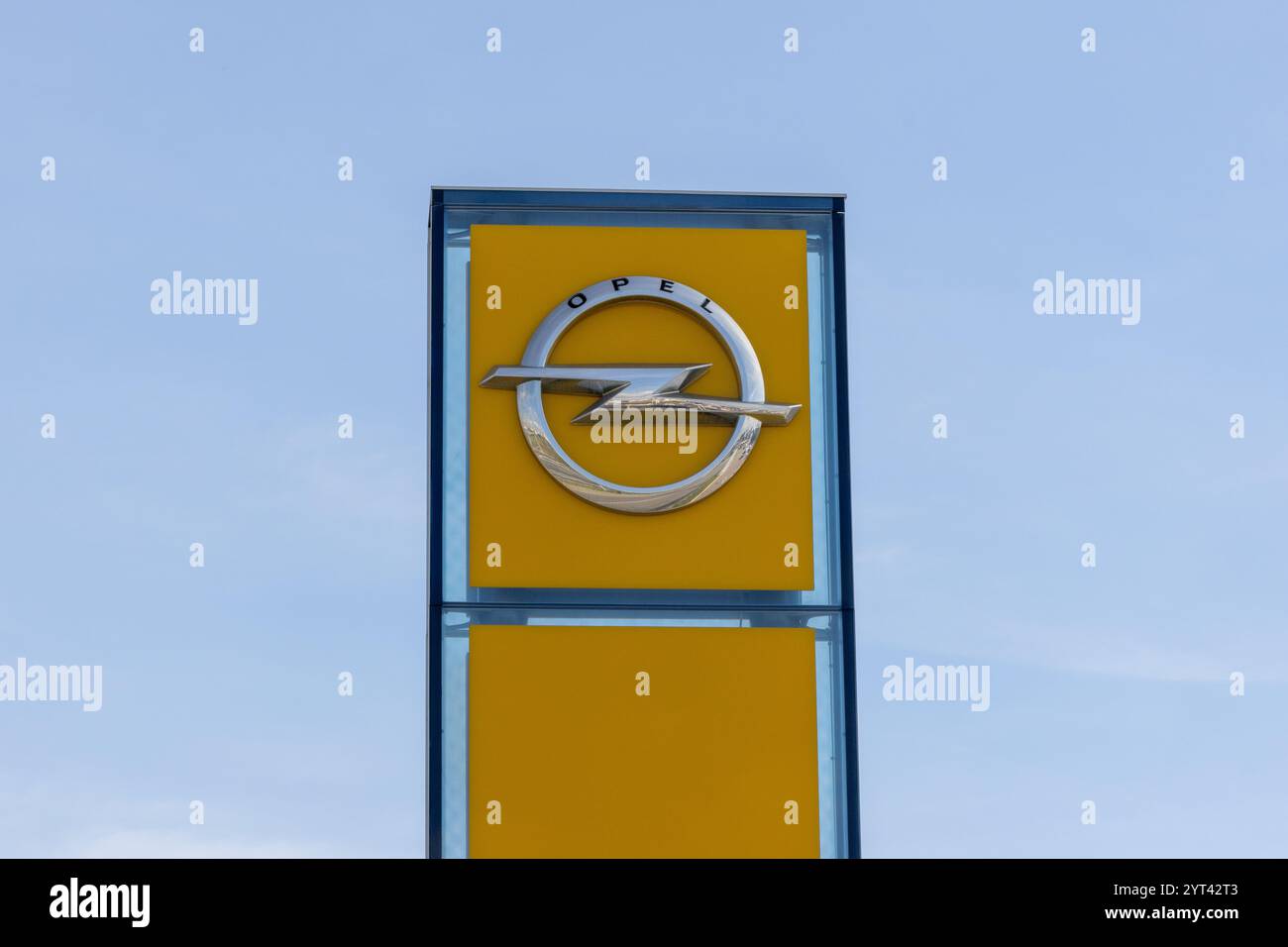 Opel logo is displayed on a large yellow sign with a clear blue sky in ...
