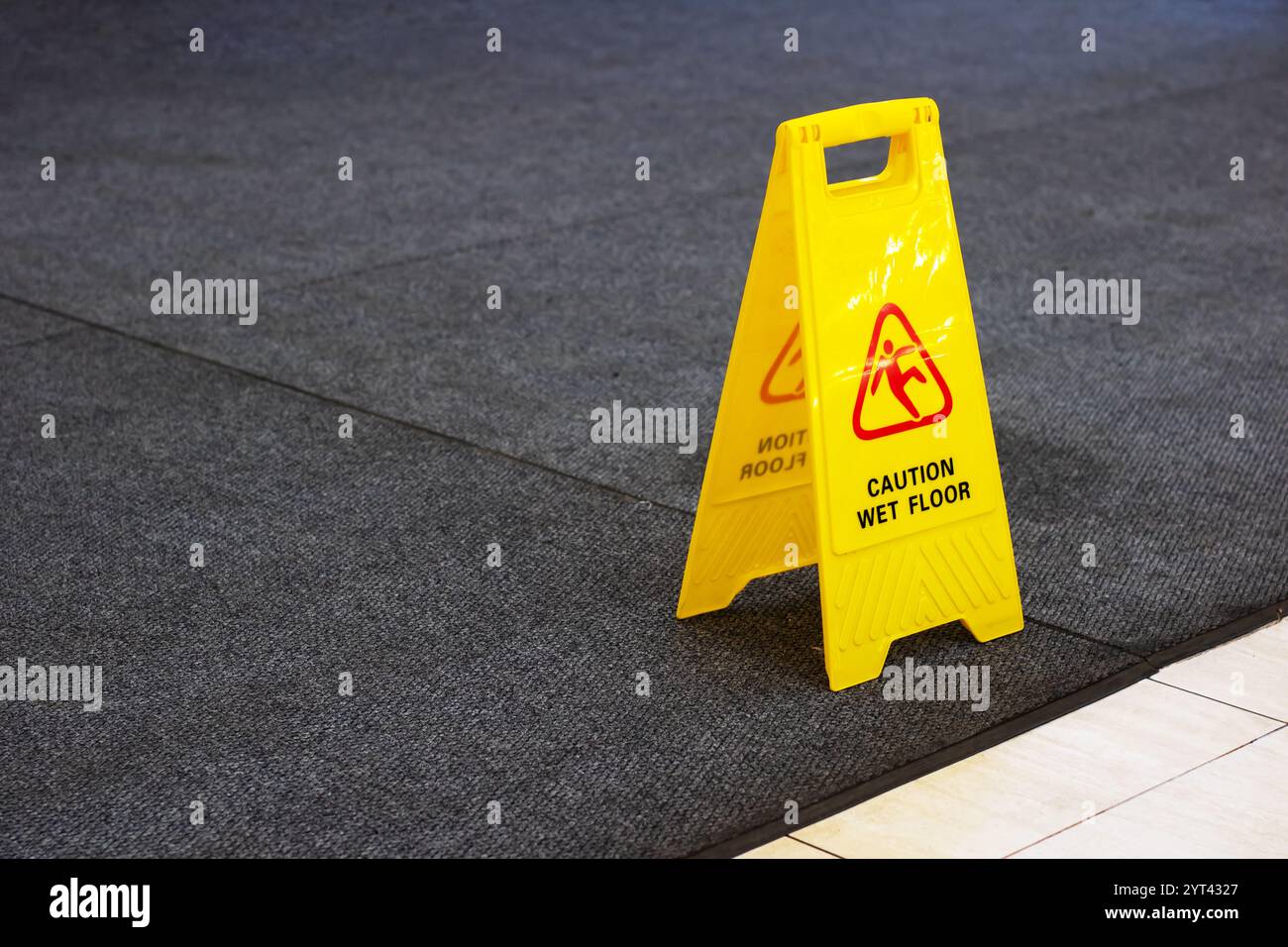 A yellow caution sign with the words Caution Wet Floor prominently ...