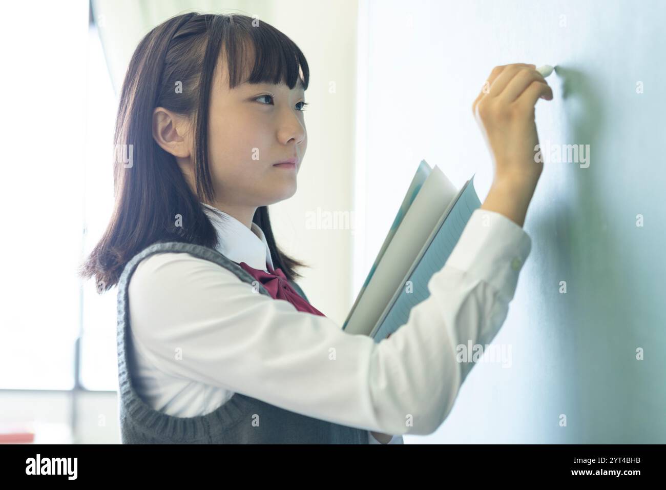 Female high school student writing on blackboard Stock Photo - Alamy