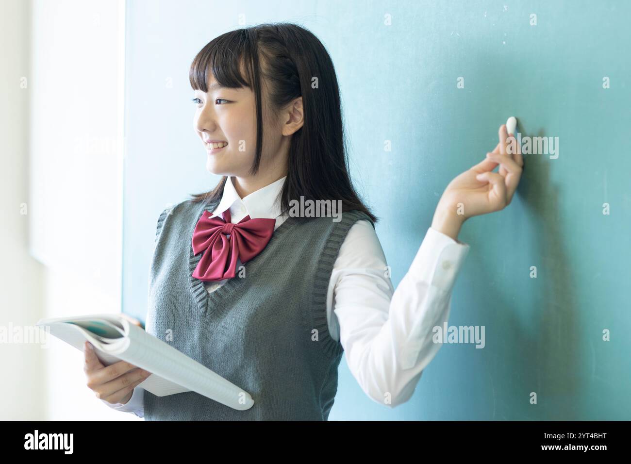 Female high school student writing on blackboard Stock Photo - Alamy
