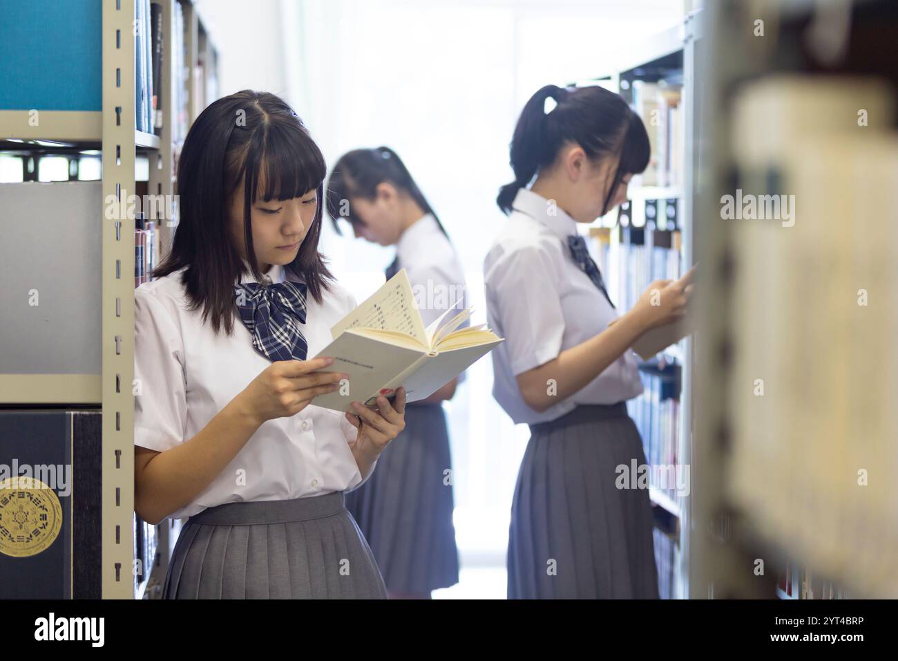 High school girls reading a book in the library Stock Photo - Alamy