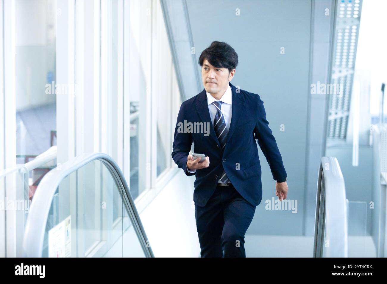 Businessman climbing an escalator Stock Photo - Alamy