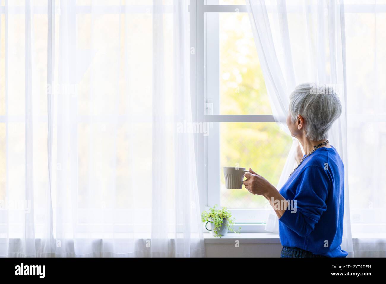 Senior woman looking out of window Stock Photo - Alamy