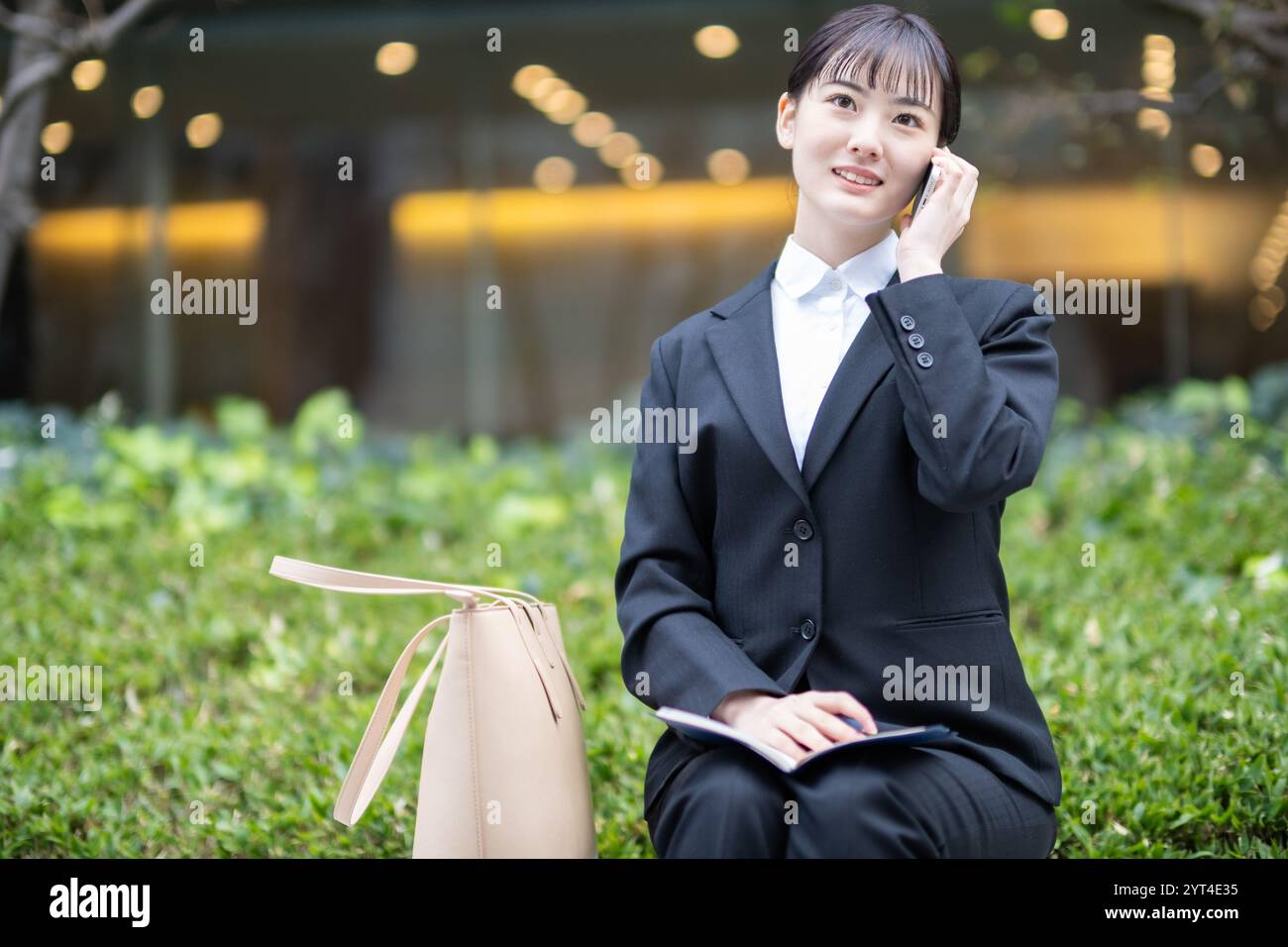 Woman making a phone call while looking at a schedule book Stock Photo ...