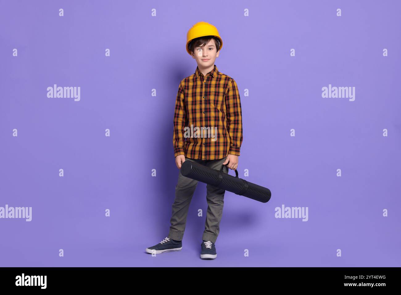 Boy with blueprint tube pretending to be architect on violet background ...