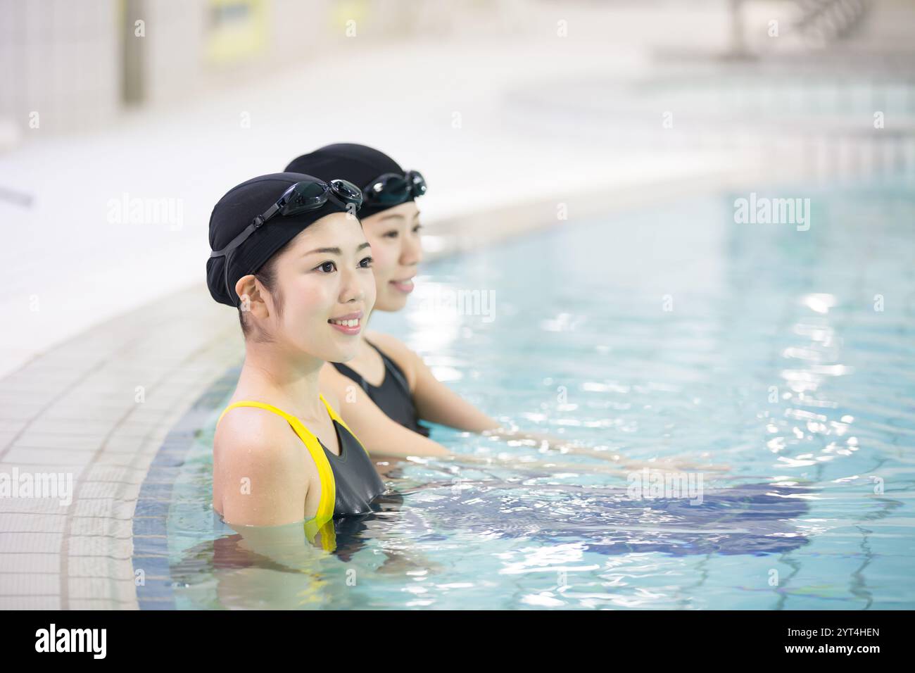 Two women in swimming costumes entering pool Stock Photo - Alamy