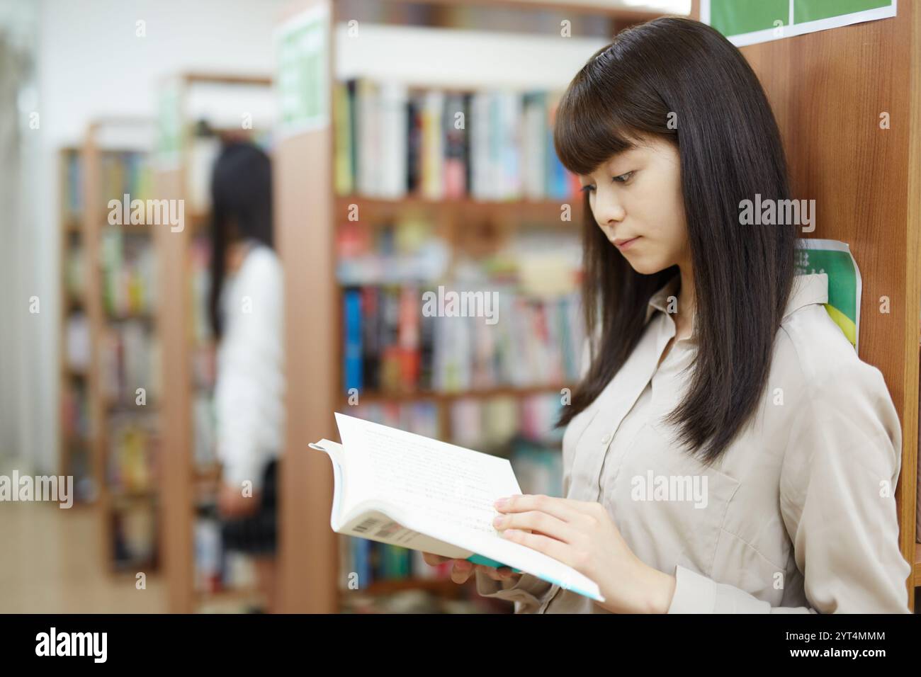 Female university student reading a book in the library Stock Photo - Alamy