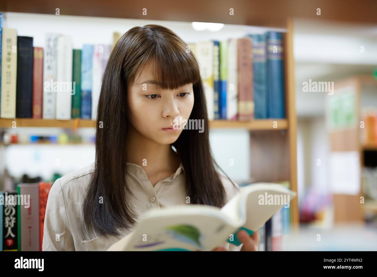 Female university student reading a book in the library Stock Photo - Alamy