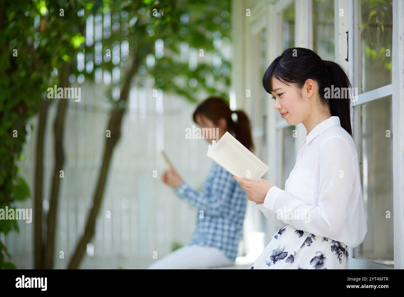 Two women reading by window Stock Photo - Alamy
