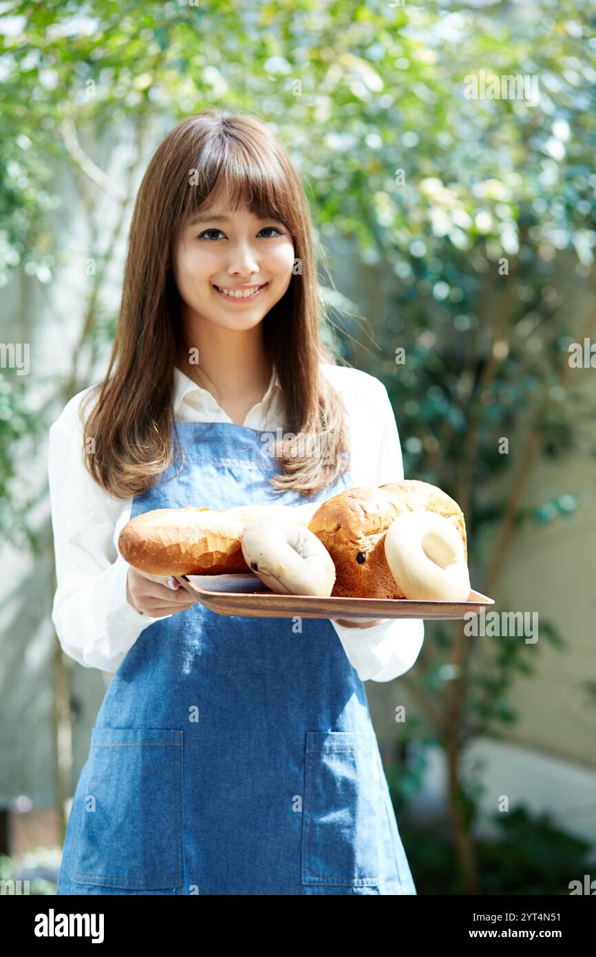 Woman in apron holding bread Stock Photo - Alamy