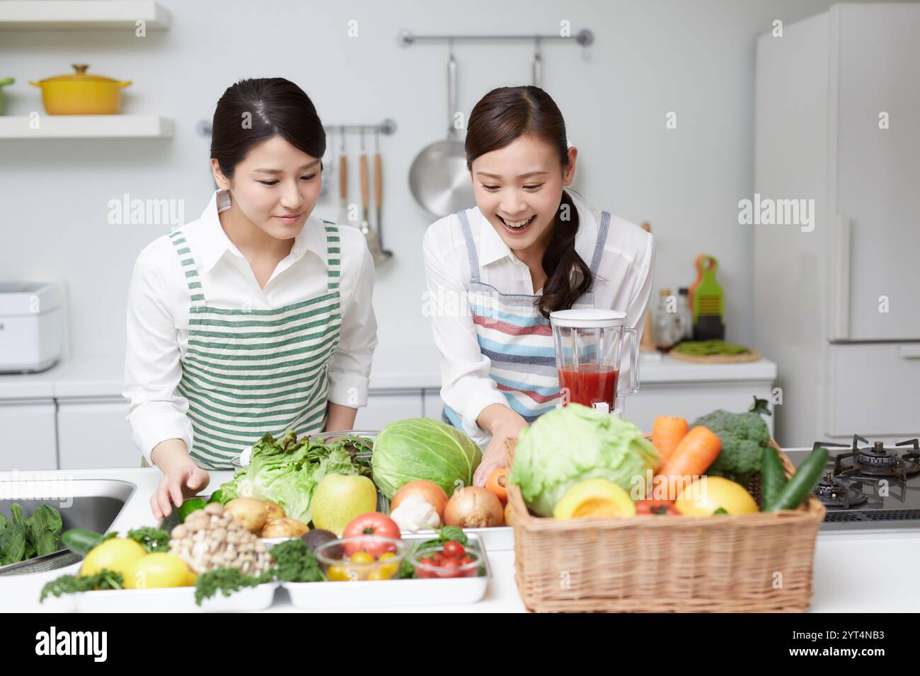 Two women making vegetable smoothies Stock Photo - Alamy