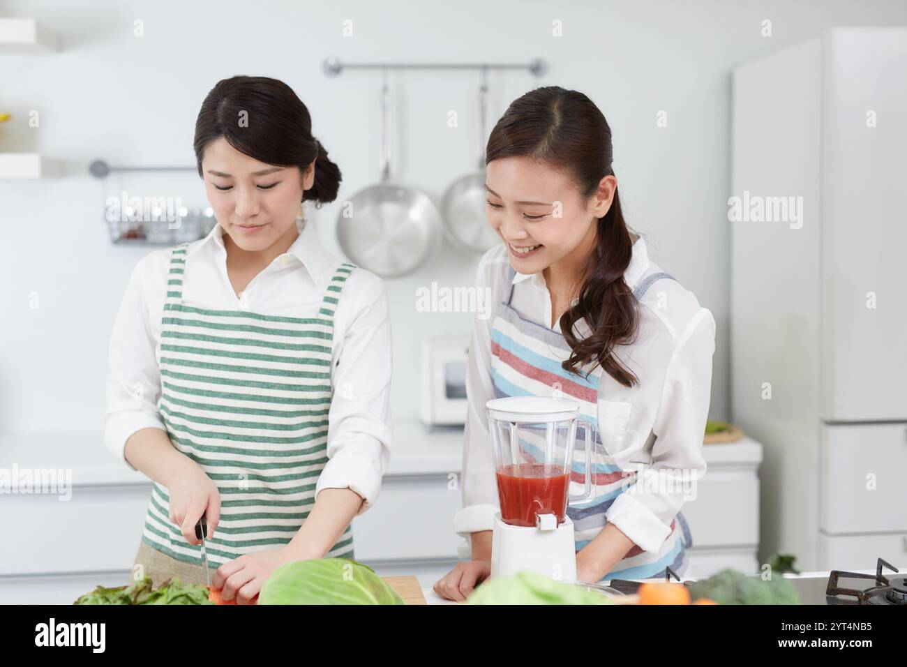 Two women making vegetable smoothies Stock Photo - Alamy