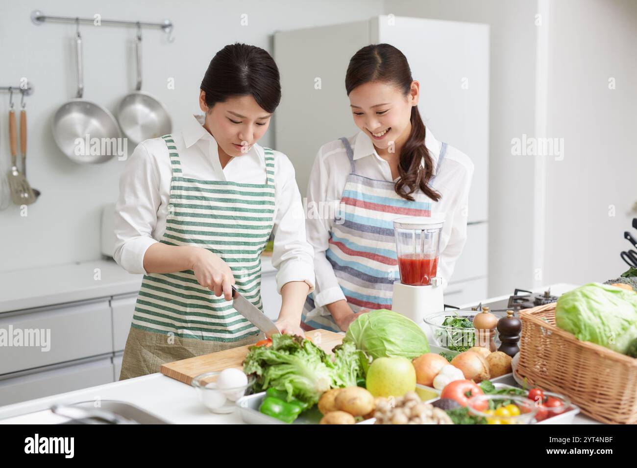 Two women making vegetable smoothies Stock Photo - Alamy