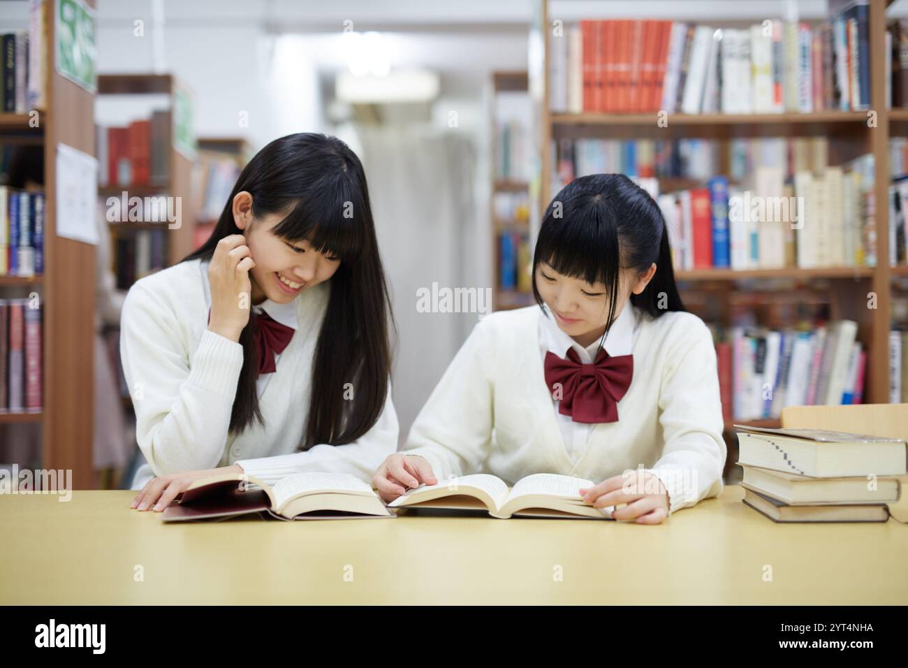 Female high school student reading a book in the library Stock Photo ...
