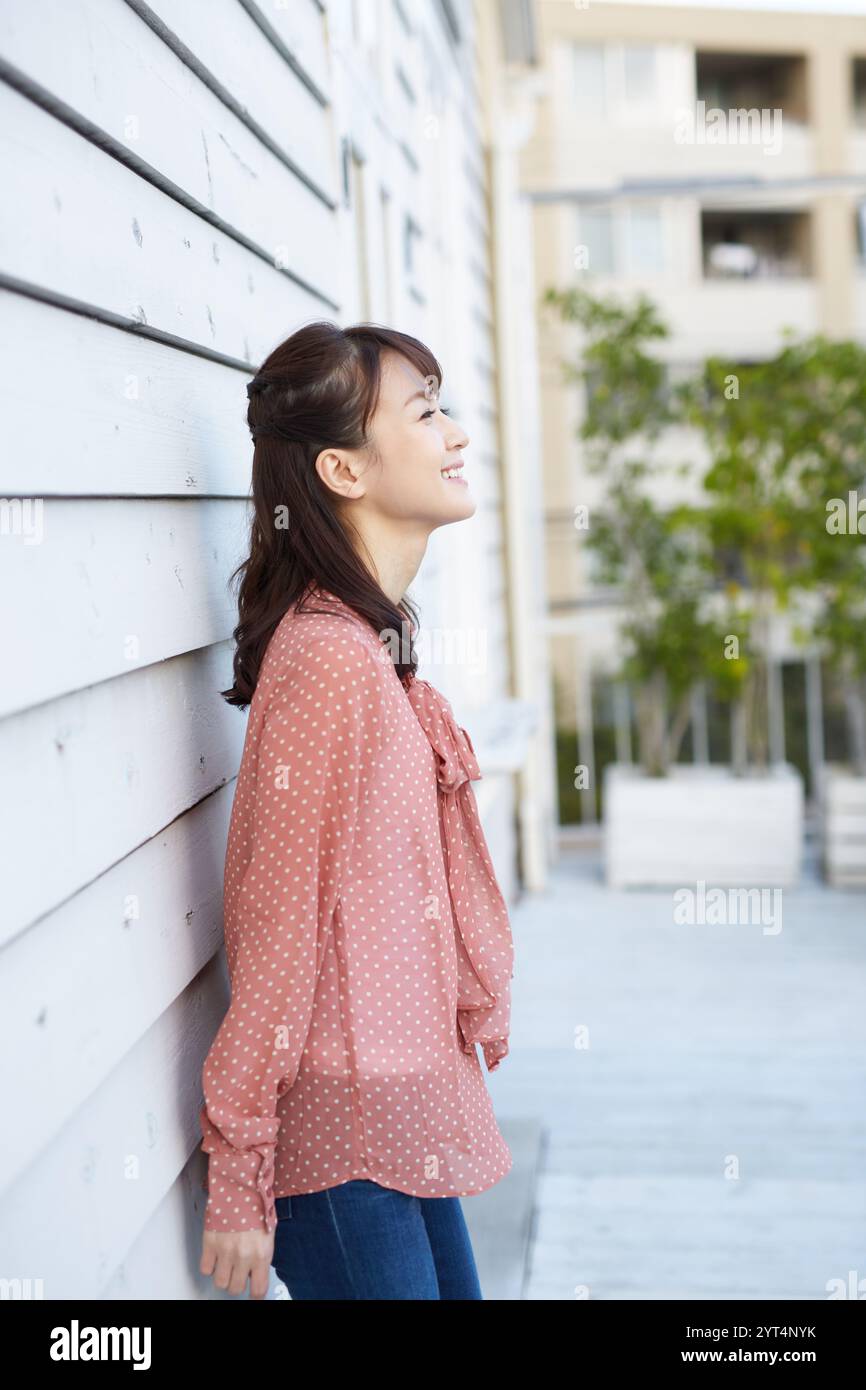 Woman leaning against wall Stock Photo - Alamy