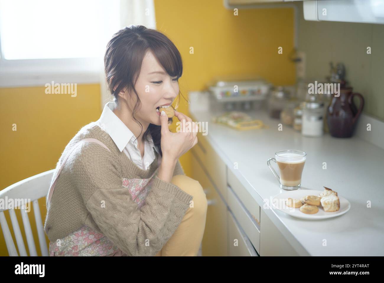 Young woman eating biscuits in the kitchen Stock Photo - Alamy