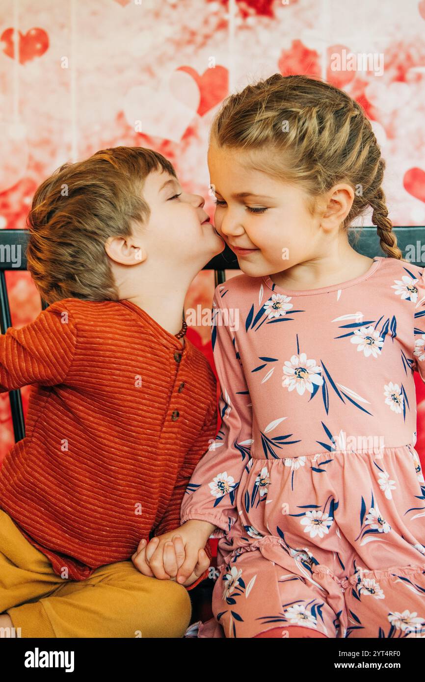 Boy kisses sister's cheek while holding hands, heart backdrop Stock ...
