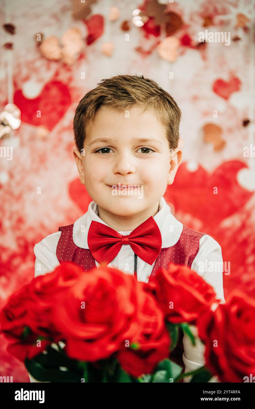 Boy in red bow tie and vest with roses, heart-themed background Stock ...