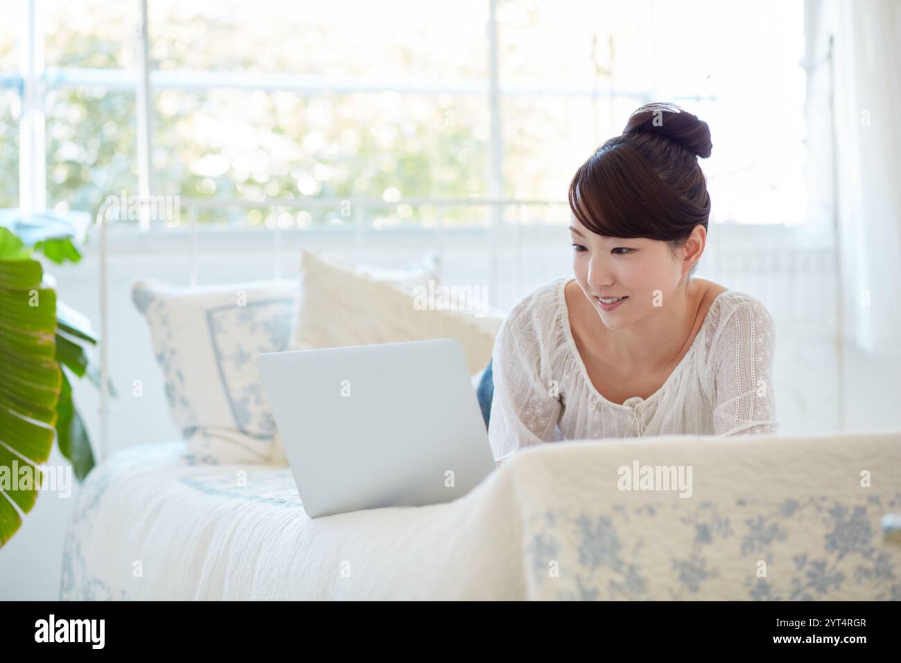 Woman using computer on bed Stock Photo - Alamy