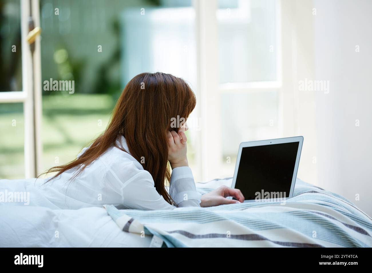 Woman using computer on bed Stock Photo - Alamy