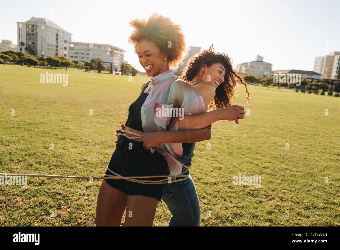 Two female friends laughing and playing outdoors. They are woven ...