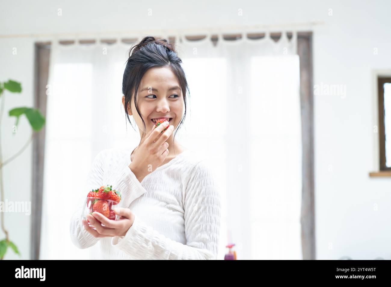 Young woman eating strawberry Stock Photo - Alamy