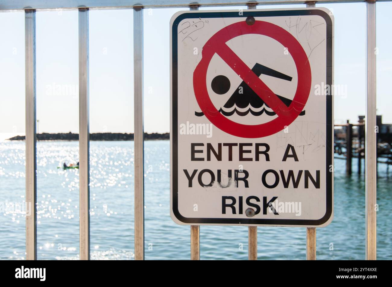 "No swimming" sign by railing overlooking a sunny waterfront Stock ...