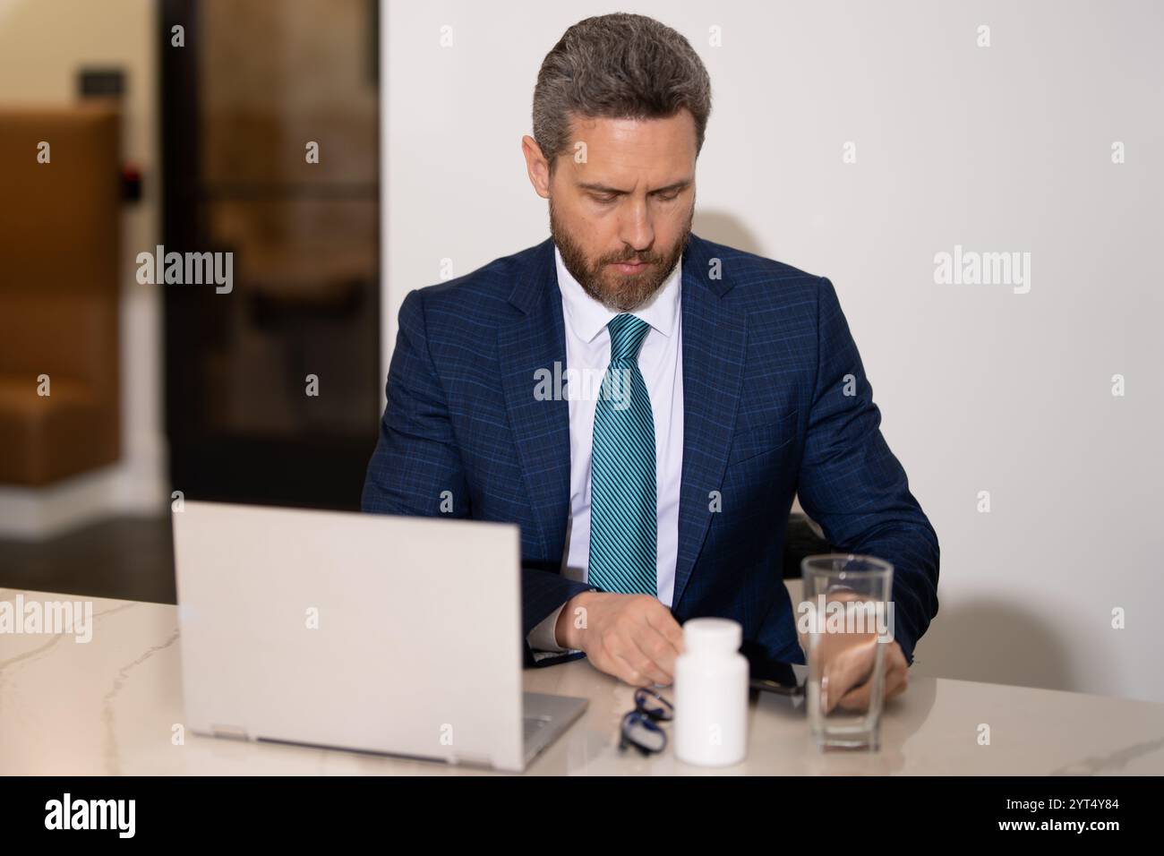 Headache, tiredness and stress. Man in suit uses a laptop, is tired got ...