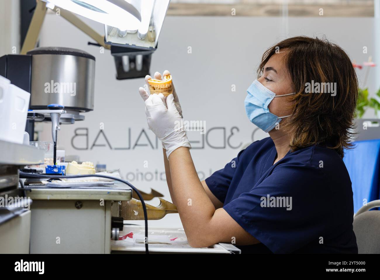 Dental lab technician wearing gloves and mask working on a prosthetic ...