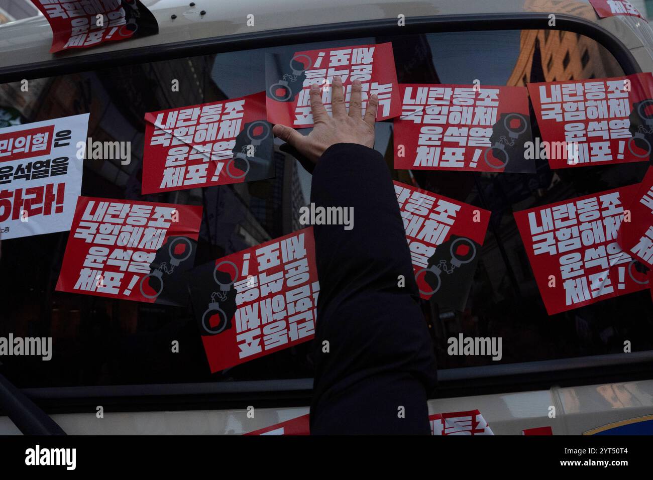A protester plasters stickers calling for the arrest of South Korean ...