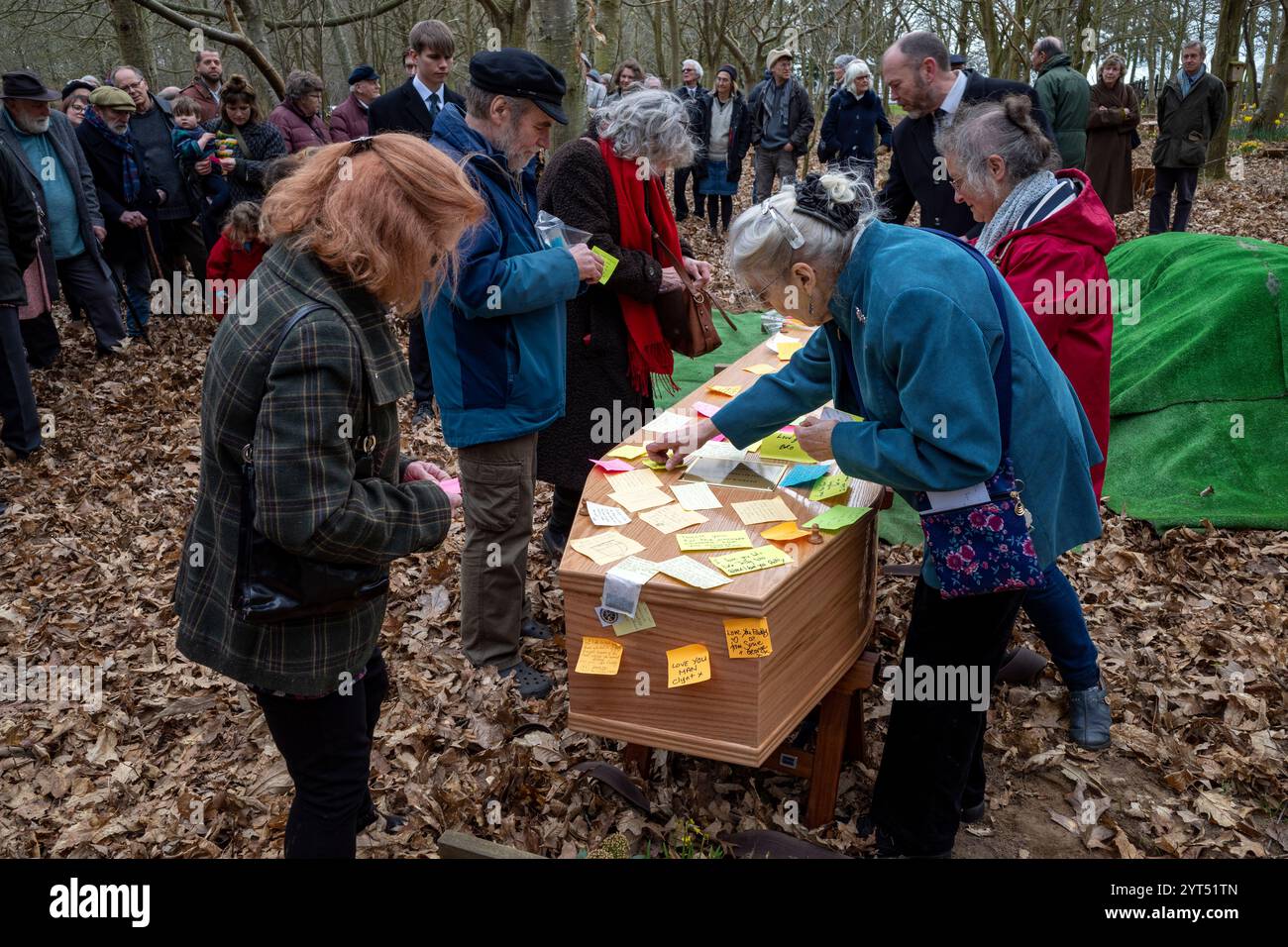 Mourners writing post-it notes on a coffin at a green burial site Stock ...