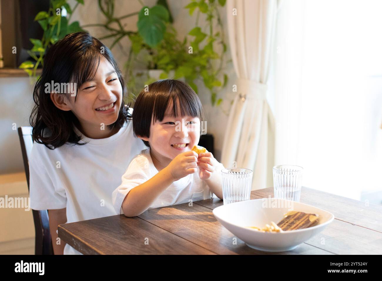 Boy sitting on sister's lap and smiling while eating a snack Stock ...