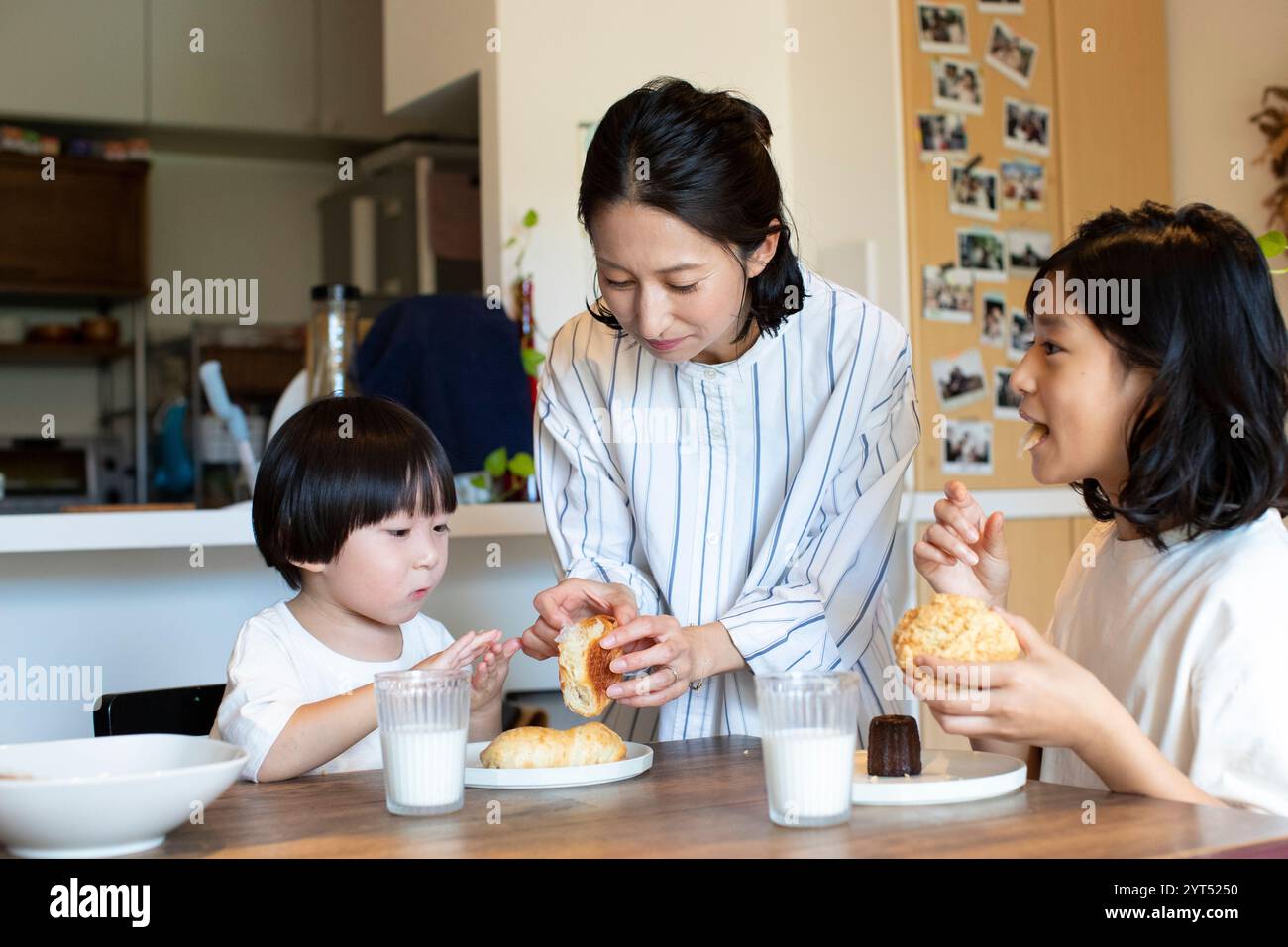 Children eating bread and mother helping them Stock Photo - Alamy