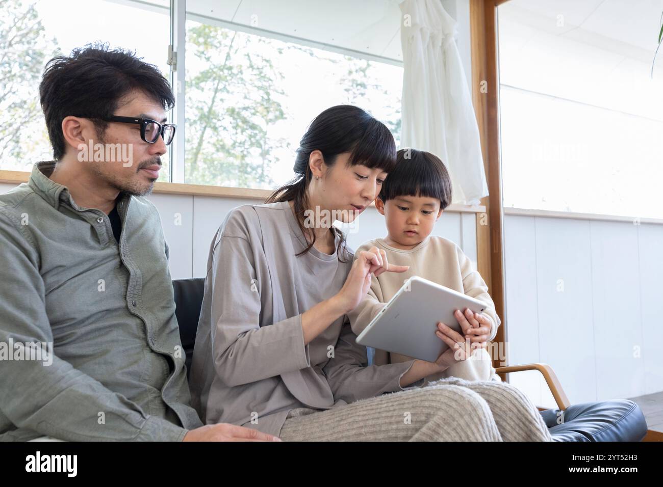 Family watching tablet in room Stock Photo - Alamy