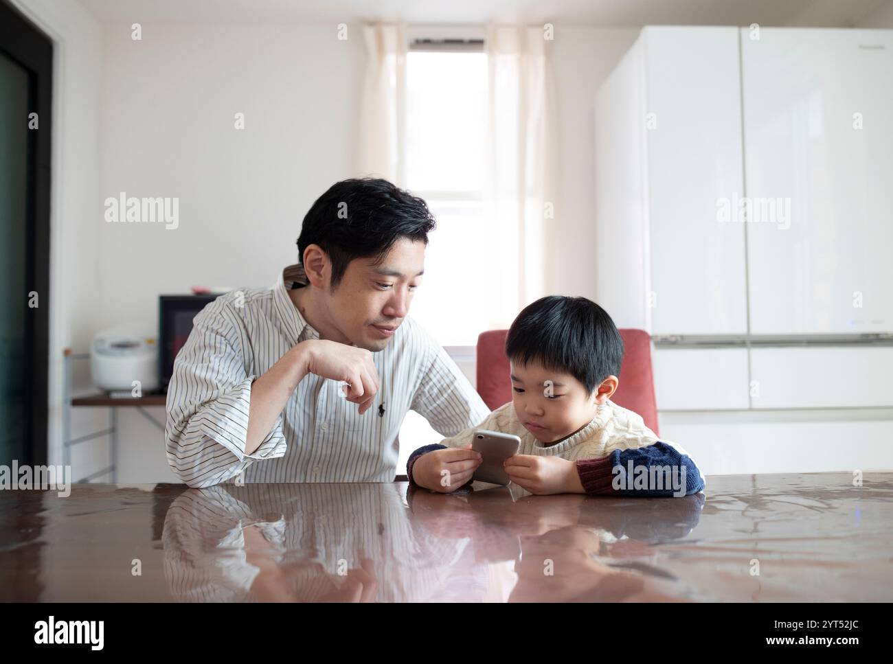 Boy and father looking at a smartphone together Stock Photo - Alamy