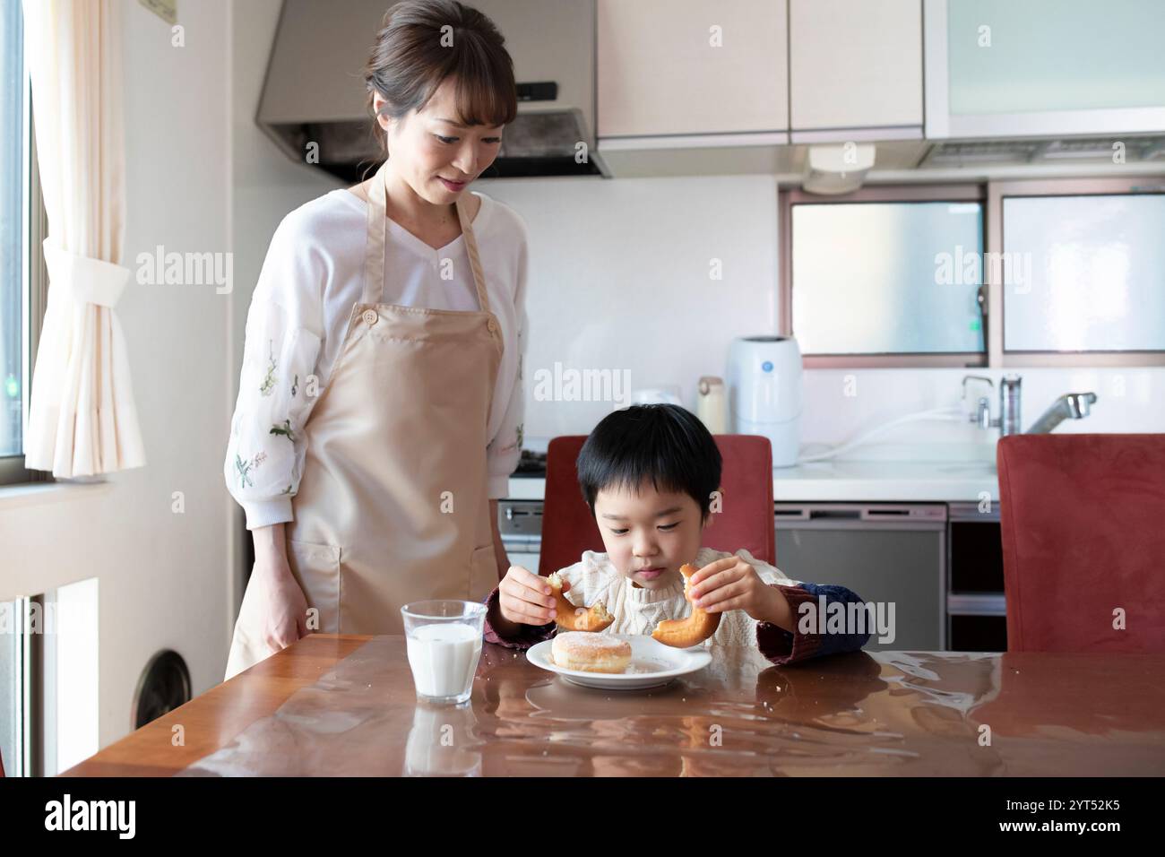 Mother watching her child eating a snack Stock Photo - Alamy